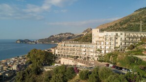 Um hotel à beira-mar com vários andares, varandas e vista para o mar.