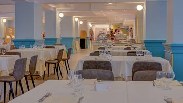 Restaurante com várias mesas, cada uma posta com talheres e copos, e uma paleta de cores azul e branca.