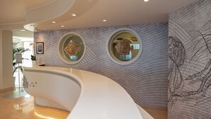 Uma área de recepção moderna, com um balcão branco curvo, duas decorações circulares na parede e um design de parede estampado.