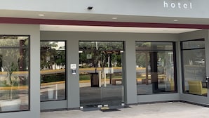 Entrada do Hotel Luma, com design moderno, portas de vidro e vista da região.