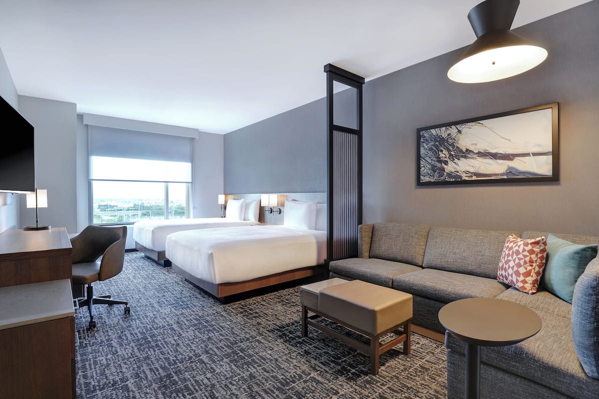 Quarto de hotel com cama, sofá, escrivaninha e cadeira.