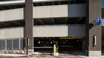 Uma garagem de estacionamento com vários níveis, sinalização clara sobre vagas disponíveis e um espaço reservado para estacionamento de deficientes.