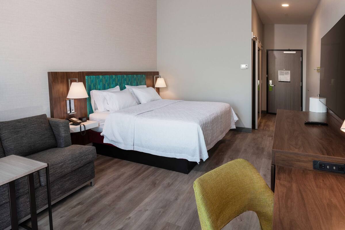 Quarto de hotel com cama, sofá, escrivaninha e cadeira.