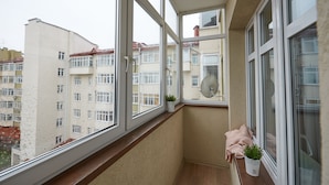 Varanda com vista para edifícios próximos, um vaso de planta e uma antena parabólica.