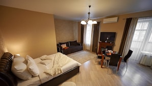 Quarto de hotel com cama, sofá, televisão, escrivaninha e cadeira.