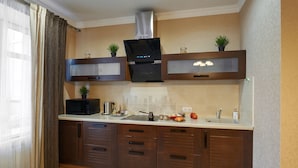 Uma cozinha moderna com armários de madeira escura, exaustor de aço inoxidável e bancada com diversos eletrodomésticos e utensílios.