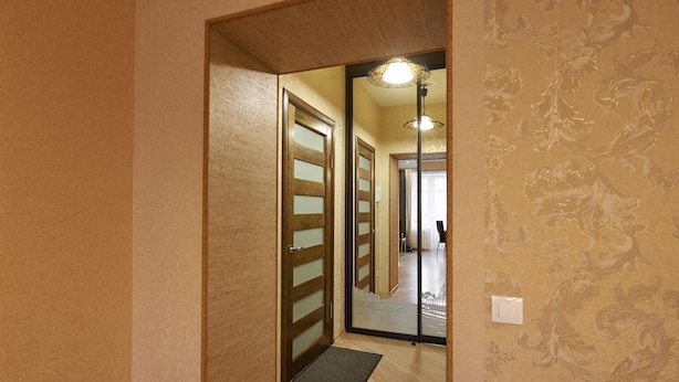 Um corredor com porta de madeira, porta de vidro e luminária.