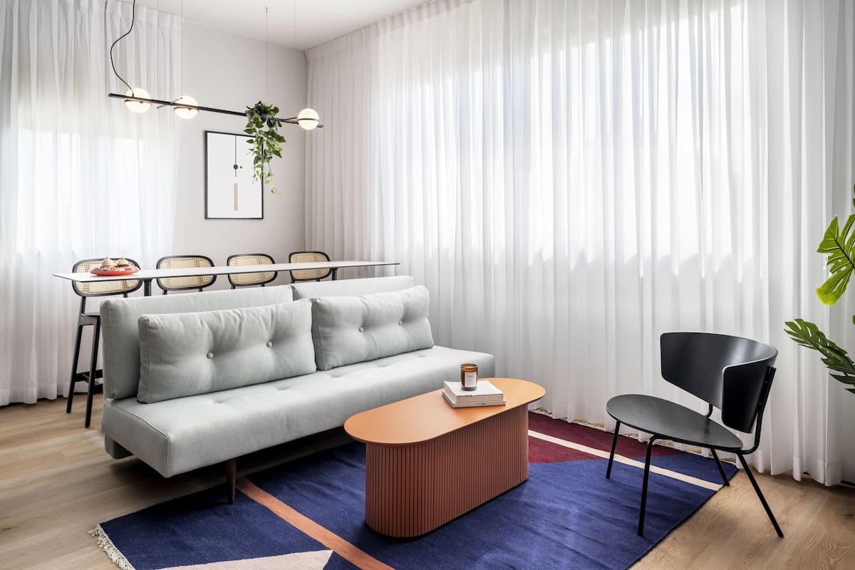 Uma sala de estar moderna com um sofá cinzento, uma mesa de centro de madeira e uma cadeira preta.