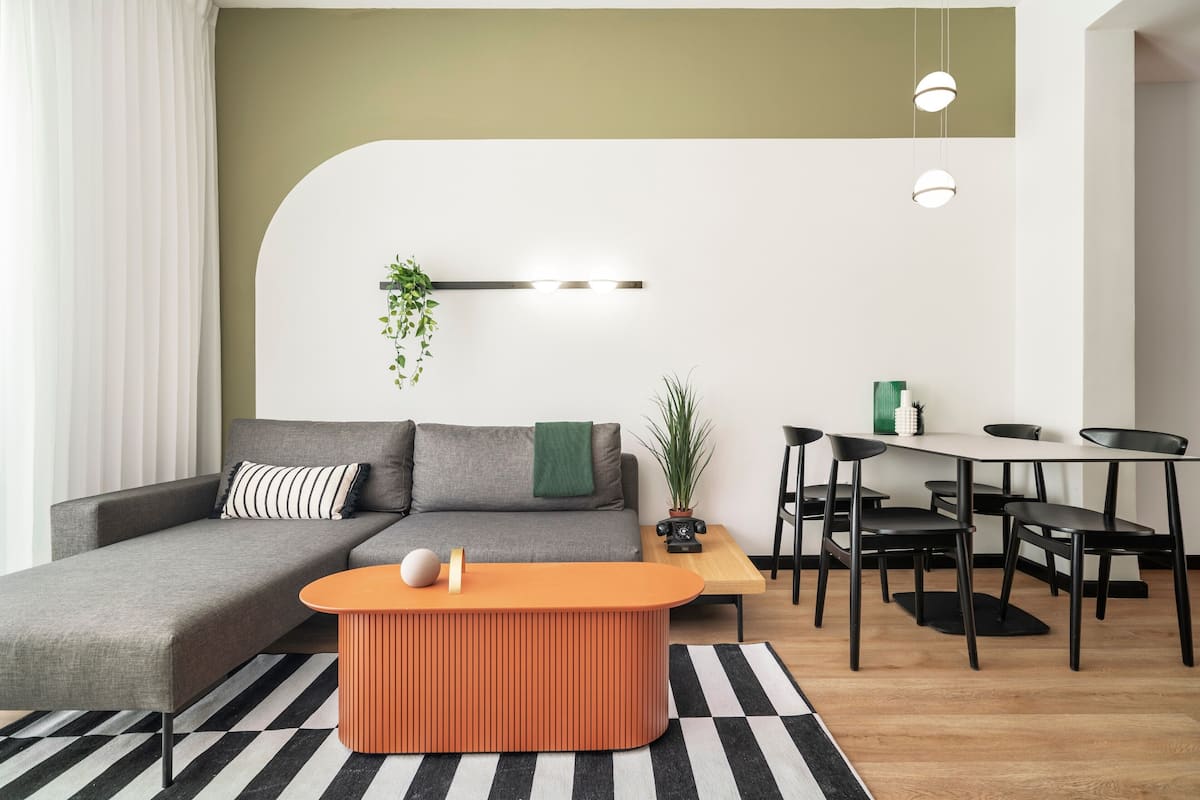Uma sala de estar moderna com sofá, mesa de centro e área de jantar.