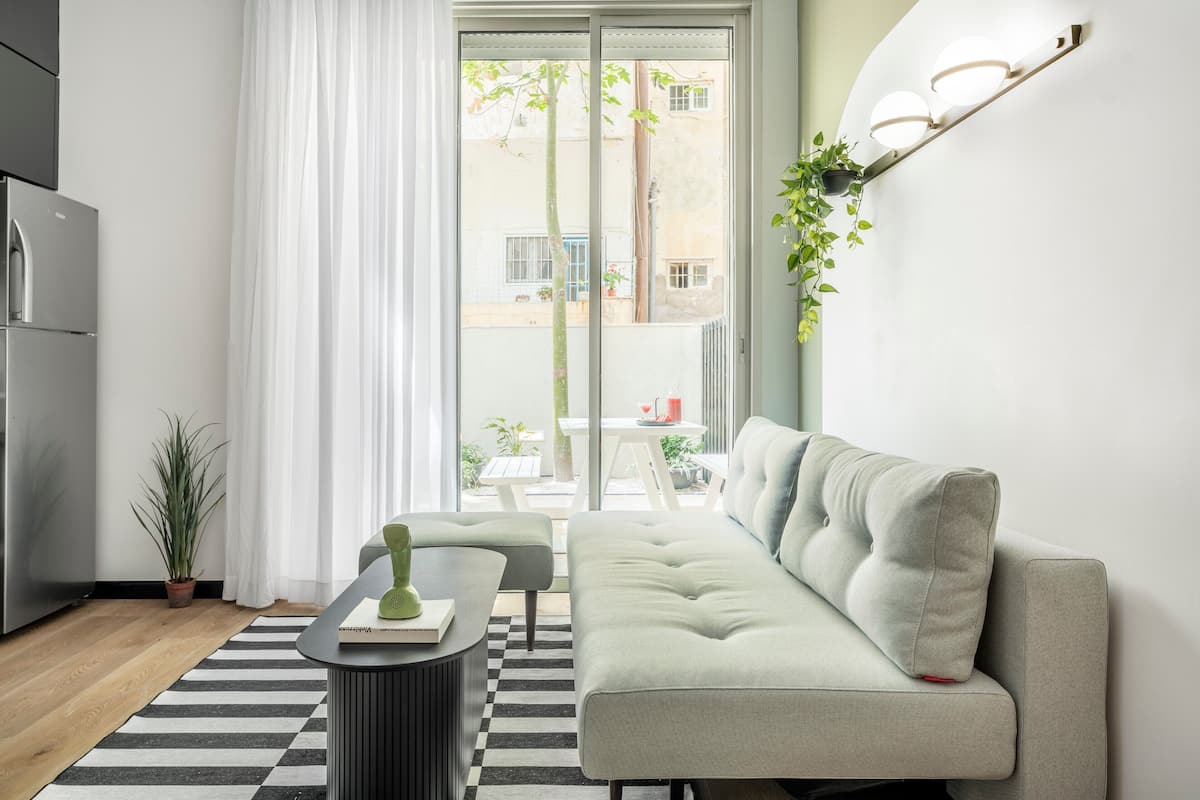 Uma sala de estar moderna com um sofá, uma mesa de centro e uma planta em vaso.
