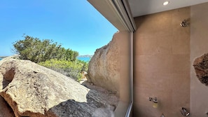 Casa de banho com vista para o mar, uma rocha grande e uma parede com azulejos.