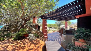 An outdoor patio area with a pergola, seating, and potted plants.