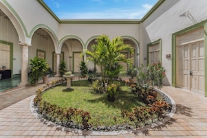 Um pátio com um jardim circular, plantas em vasos e uma piscina.