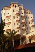 Hotel com vários andares, varandas, teto plano e céu claro.