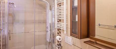 Um banheiro moderno com box de vidro, vaso sanitário branco, toucador com pia e espelho.