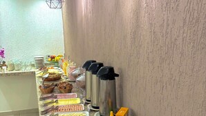 Disposição de buffet com diversos alimentos, incluindo pão, doces e uma variedade de acompanhamentos.