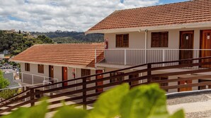 Um edifício com telhado de telhas vermelhas, varanda e guarda-corrimão branco.