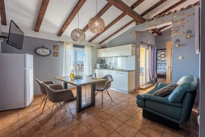 Uma cozinha compacta com área de refeições, um sofá e uma TV fixada na parede.