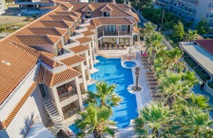 Hotel com vários andares, piscina central rodeada por palmeiras e áreas de lazer.