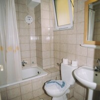 Casa de banho com banheira, sanita e lavatório, e um espelho.