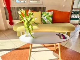 Uma sala de estar com sofá, mesa de centro e um vaso de flores.
