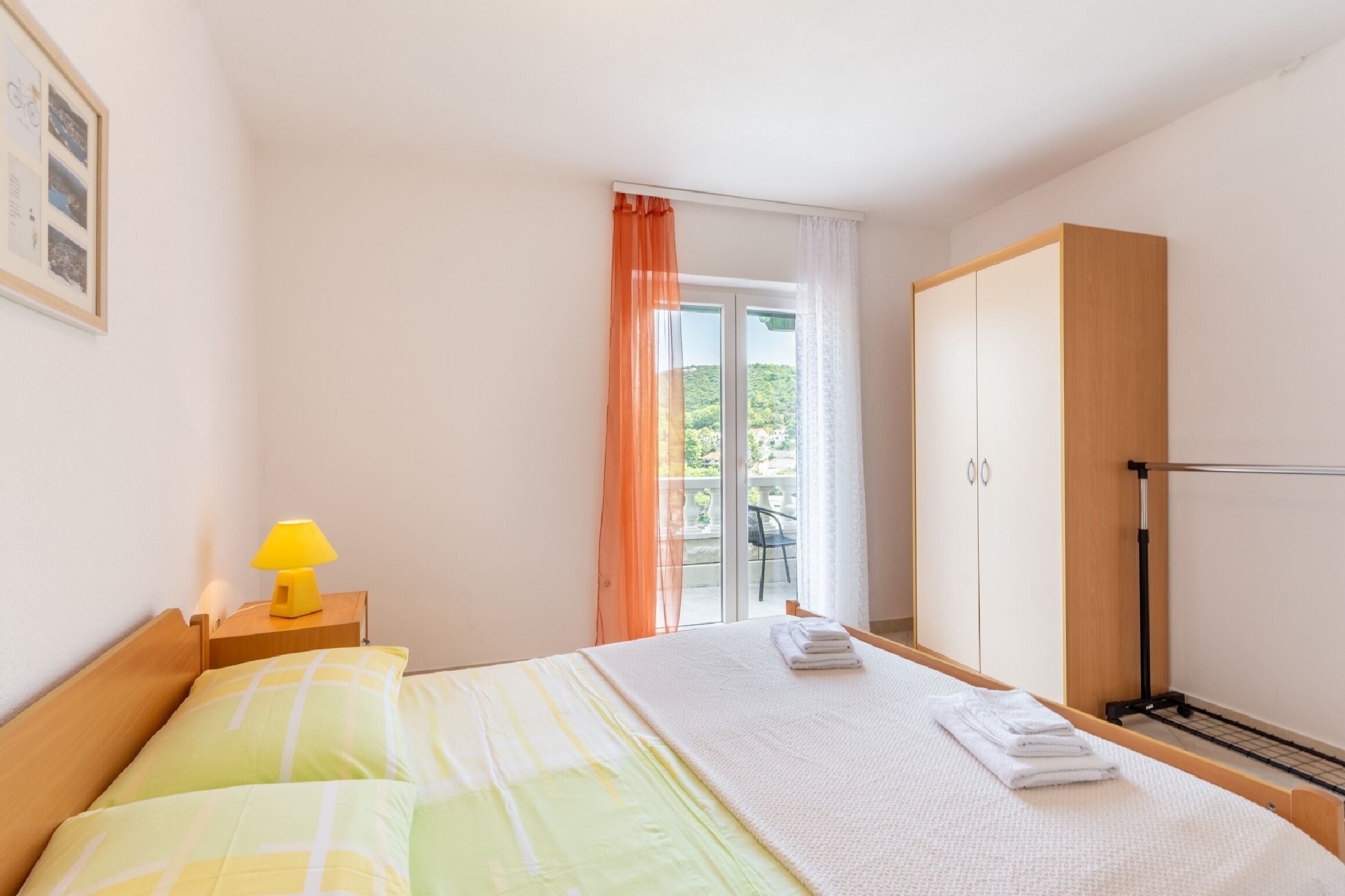 Quarto com cama, mesa de cabeceira com abajur, armário e porta de correr para o exterior.