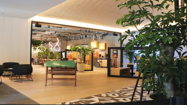Espaço moderno em ambiente interno com mesa de bilhar, área de estar e diversas plantas.