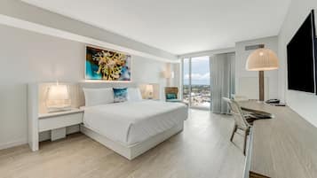 Quarto de hotel moderno com uma cama grande, abajures, escrivaninha e uma ampla janela com vista para a cidade.
