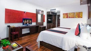 Quarto de hotel com cama, escrivaninha, televisão e obras de arte nas paredes.