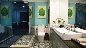 Uma casa de banho moderna com cabine de chuveiro em vidro, sanita branca e uma grande pia branca com espelho.