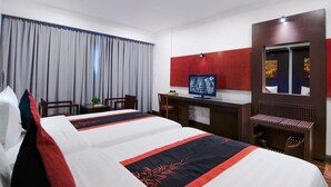 Quarto de hotel com duas camas, uma mesa, uma televisão e um espelho.