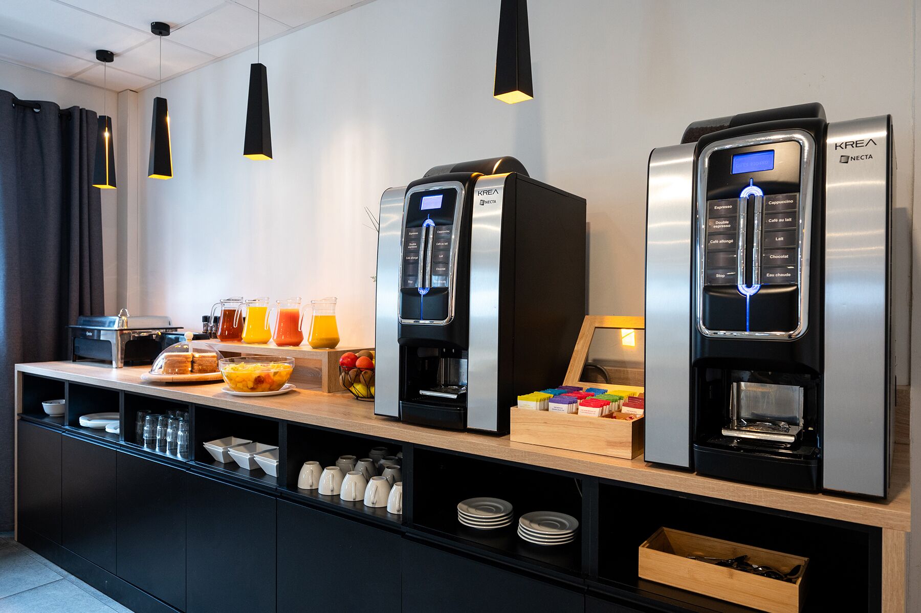 Cozinha moderna com duas máquinas de café KREA Necta, uma fruteira e diversos utensílios de cozinha.