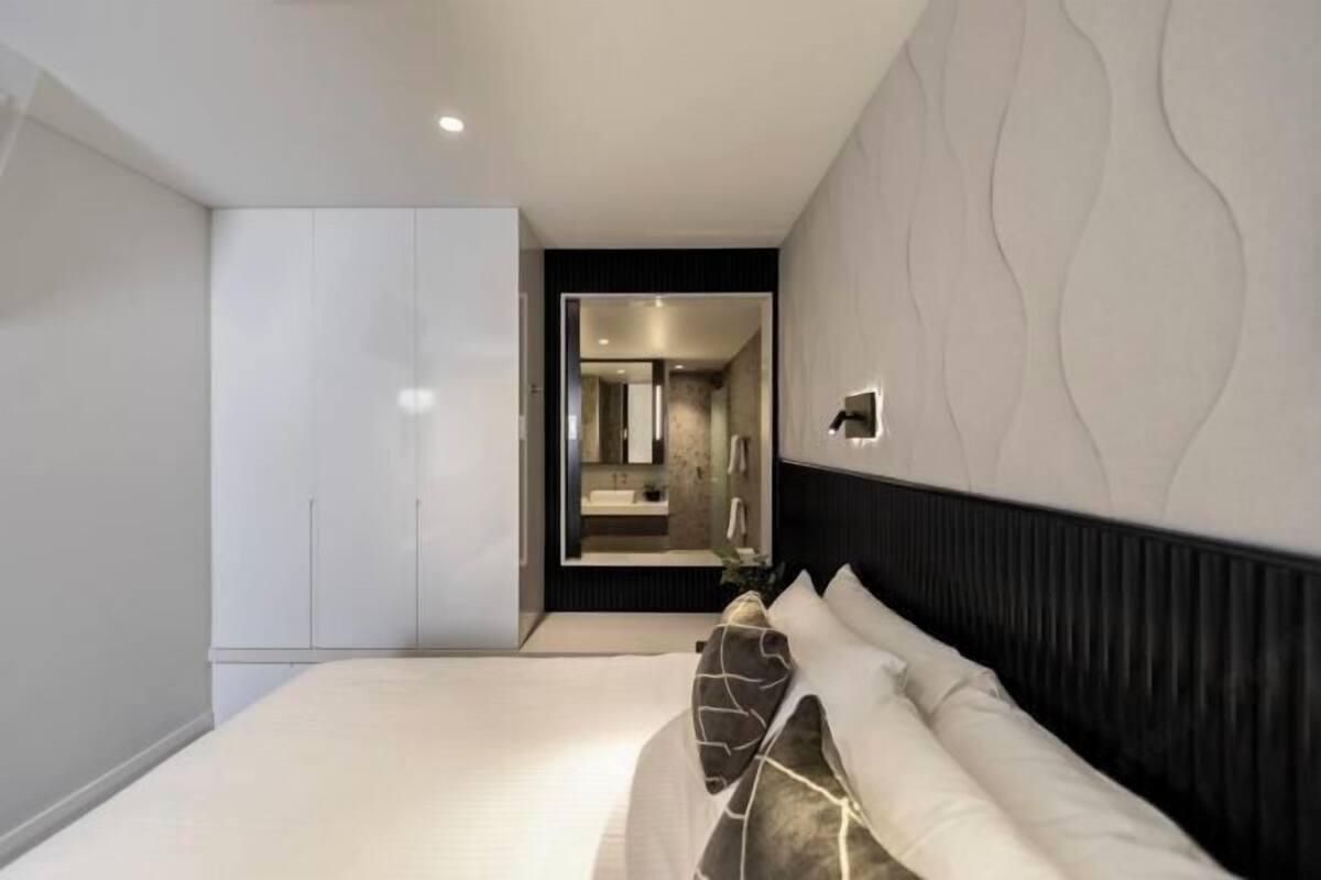 Um quarto moderno com uma cama, um guarda-roupa, um espelho e uma parede com um padrão ondulado.