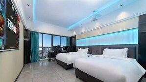 Quarto de hotel moderno com duas camas, uma escrivaninha e uma janela ampla.