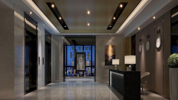 Um hall de hotel moderno com uma mesa de recepção, um relógio de parede grande e um painel decorativo exibindo uma vista urbana.