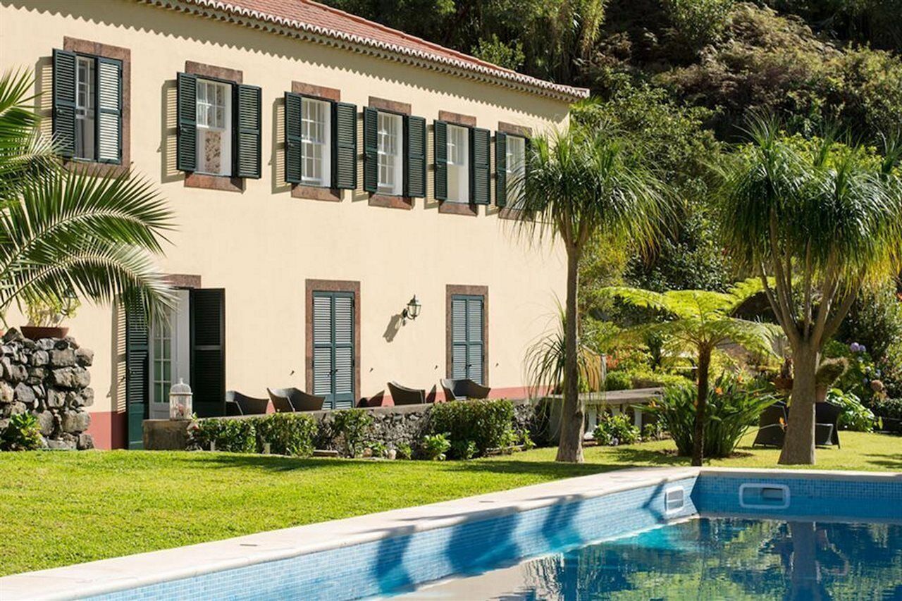 Um edifício com piscina, rodeado por vegetação e palmeiras.
