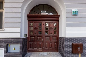 Uma porta dupla de madeira com uma placa acima, uma caixa de correio e uma placa com o número do edifício.