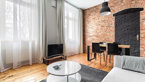 Uma sala de estar moderna com parede de tijolos, lareira, área de jantar e televisão.