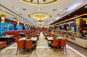 Um restaurante com várias mesas e cabines, um lustre central e um balcão com diversos itens.
