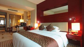 Quarto de hotel com cama grande, mesas de cabeceira, escrivaninha e espelho.