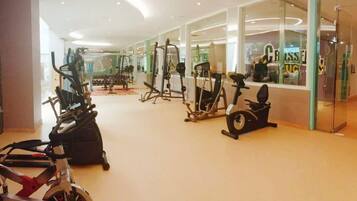 Academia com diversos equipamentos de exercício, incluindo esteiras, bicicletas ergométricas e aparelhos de musculação.