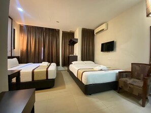 Quarto de hotel com duas camas, uma escrivaninha, uma cadeira, uma televisão de tela plana e um aparelho de ar condicionado.