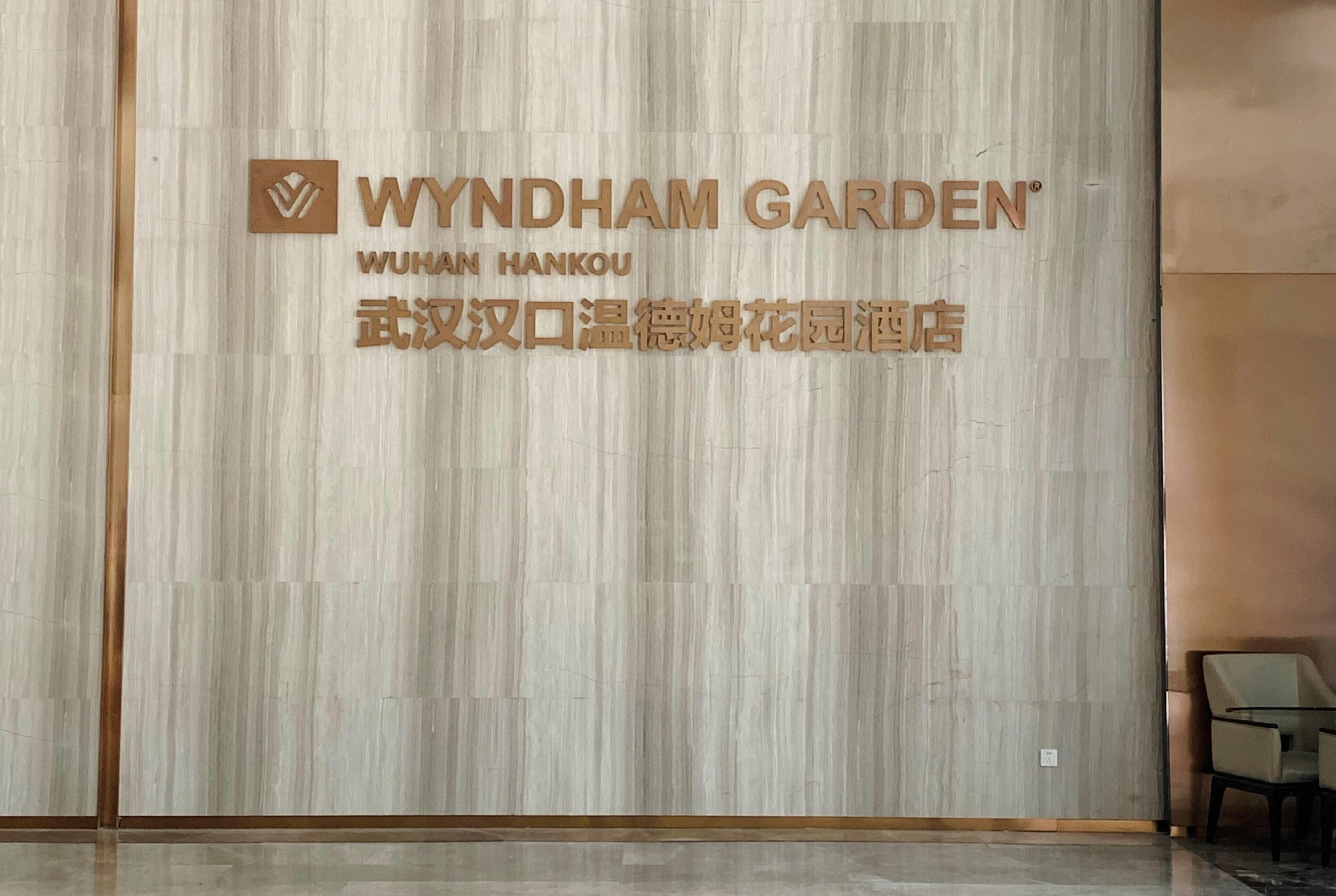 Pared de madeira com o logotipo WYNDHAM GARDEN e caracteres chineses.