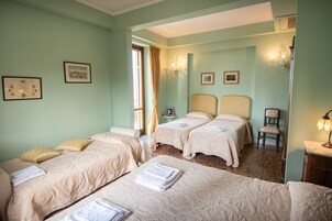 Quarto de hotel com duas camas, uma cadeira, uma mesinha e um espelho.