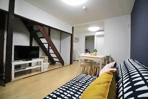 Uma sala de estar moderna com televisão, escada, área de jantar e sofá.