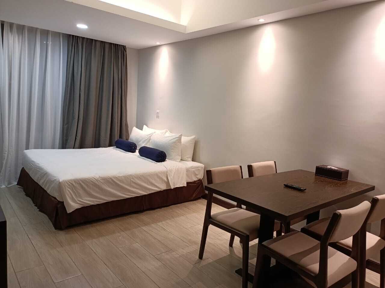 Quarto de hotel moderno com cama, mesa e cadeiras.