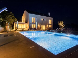 Piscina com borda azulejada, rodeada por um deck pavimentado.