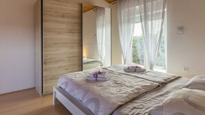 Quarto com teto de madeira, um espelho grande e janela com cortinas finas.