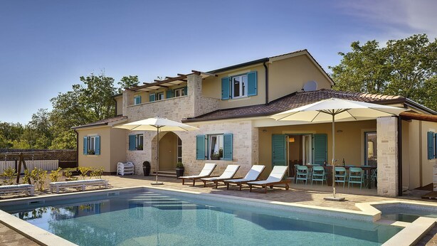 Uma casa de dois andares com piscina, área de estar externa e um pátio.
