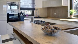 Cozinha moderna com uma ilha grande, eletrodomésticos de aço inoxidável e vista para o exterior.
